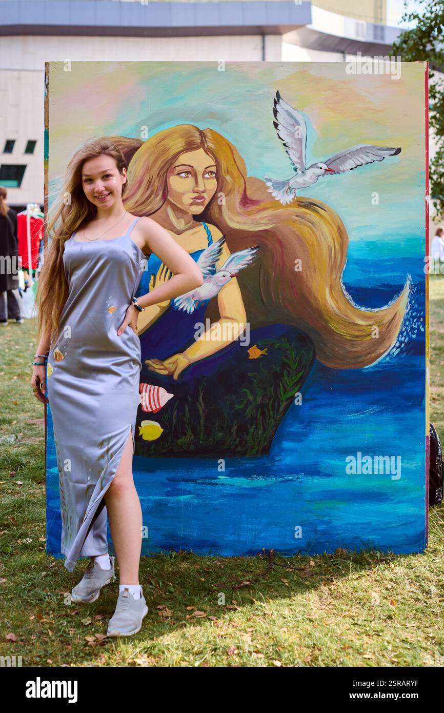 Young female with long blonde hair stands next to vibrant mermaid ...