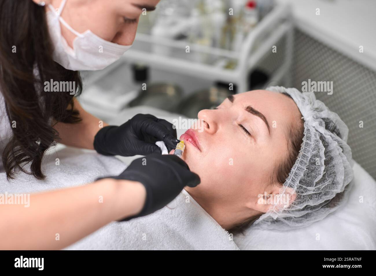 Professional performs lip filler injection on adult woman in clinical ...