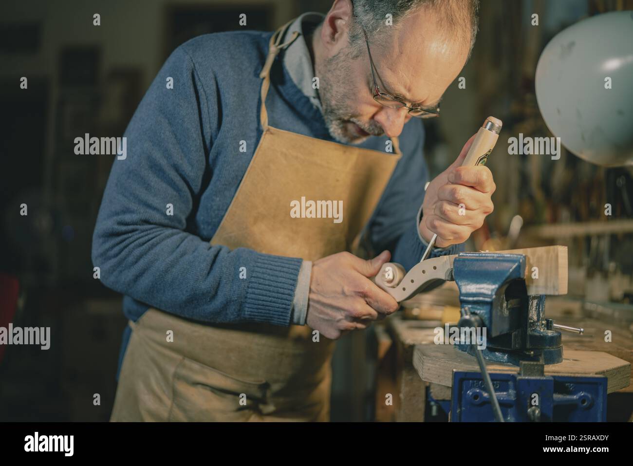 Italian luthier carefully carving a violin scroll with a gouge in a ...