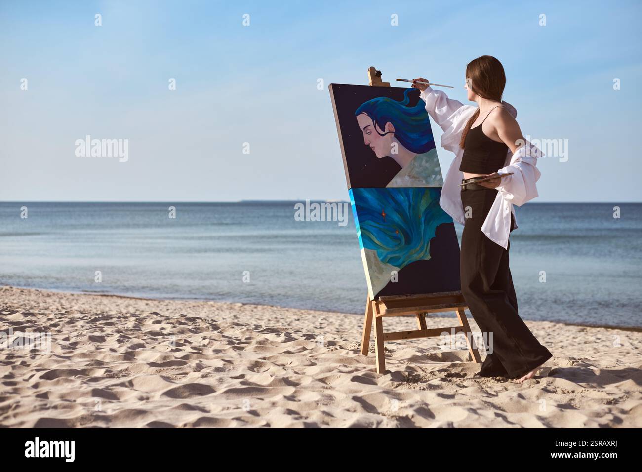 Young woman artist paints vibrant portrait on sandy beach, capturing ...
