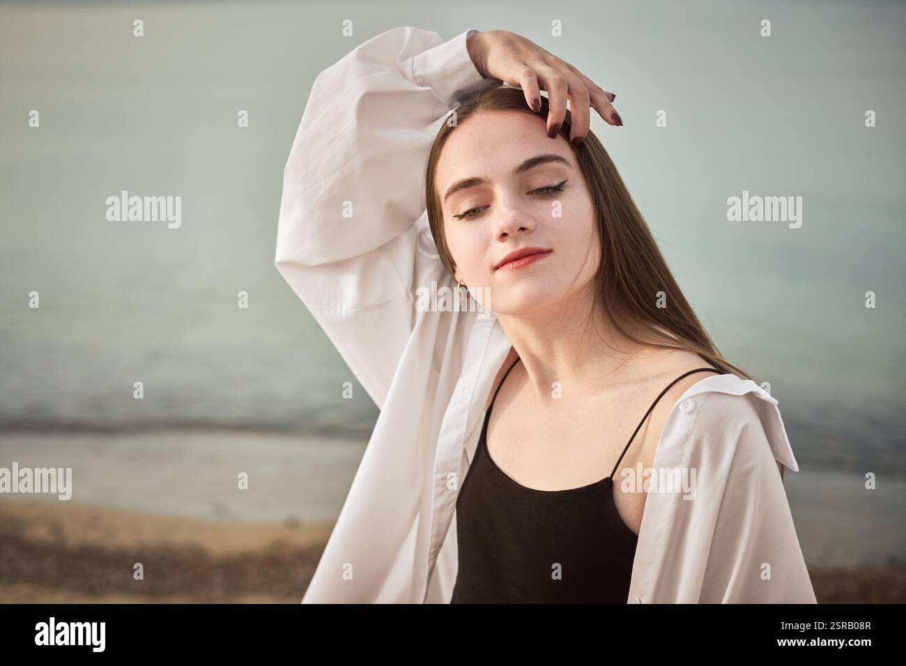 Young woman in white shirt and black top poses with confidence by ...