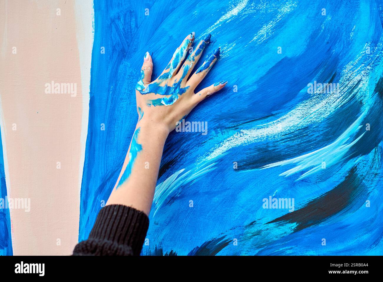 Adult female hand covered in vibrant blue paint creates expressive ...
