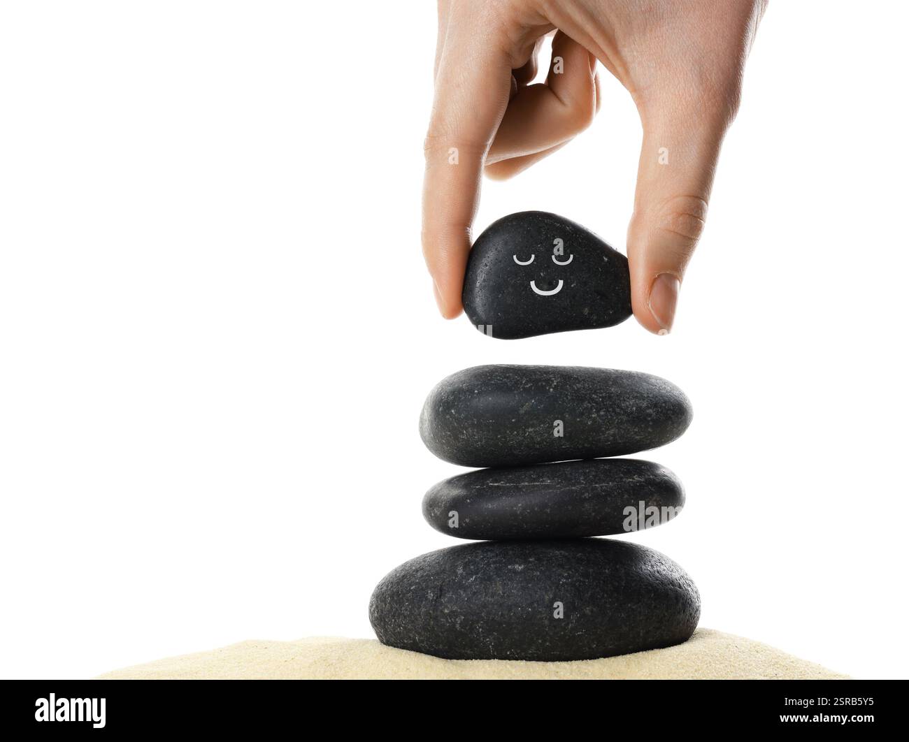 Woman putting stone with drawn smiley face on stack against white ...