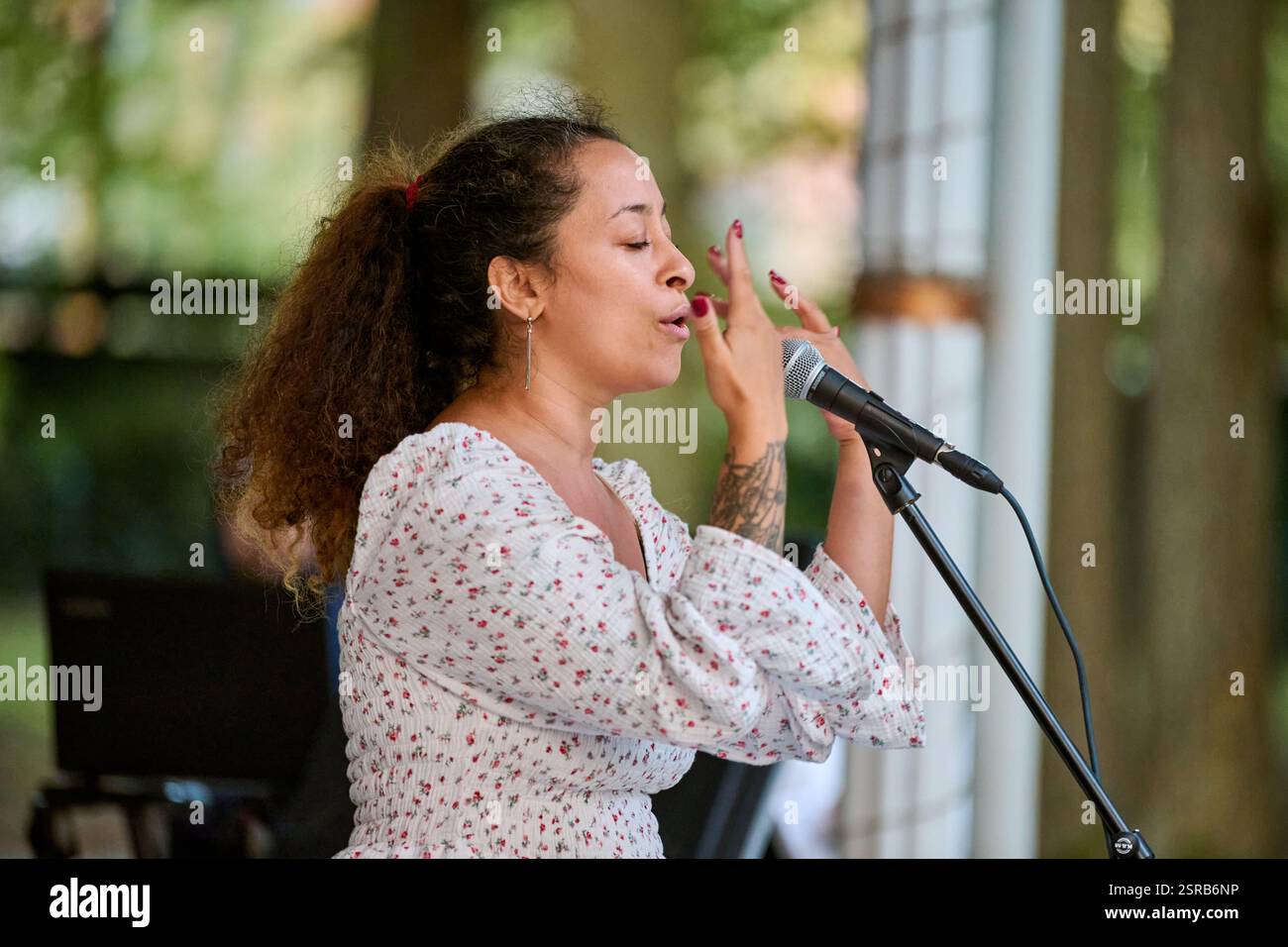 Kaliningrad, Russia - 10.08.2024 - Young woman sings passionately into microphone outdoors ...