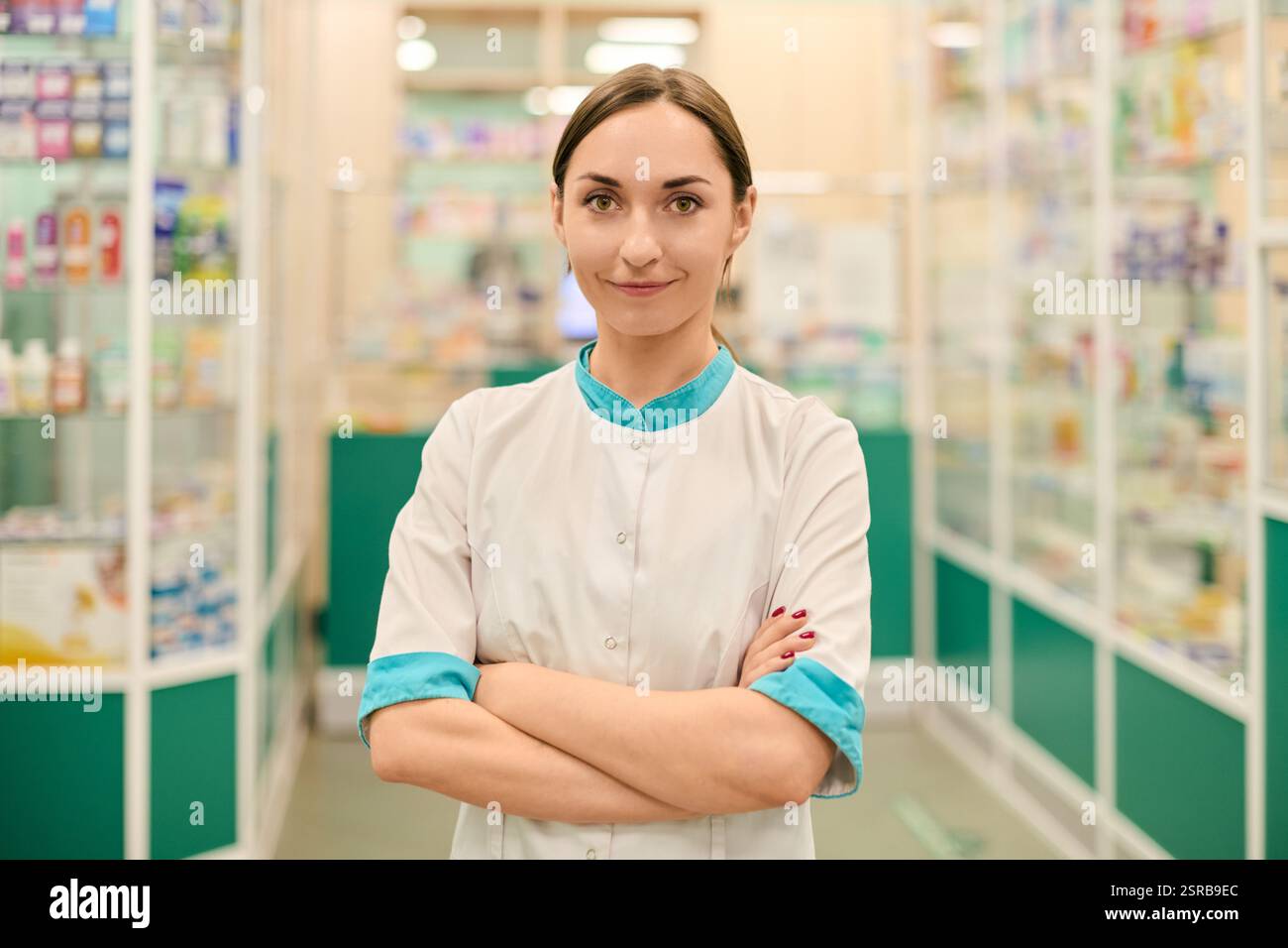 Young caucasian female pharmacist with brown hair stands confidently in ...