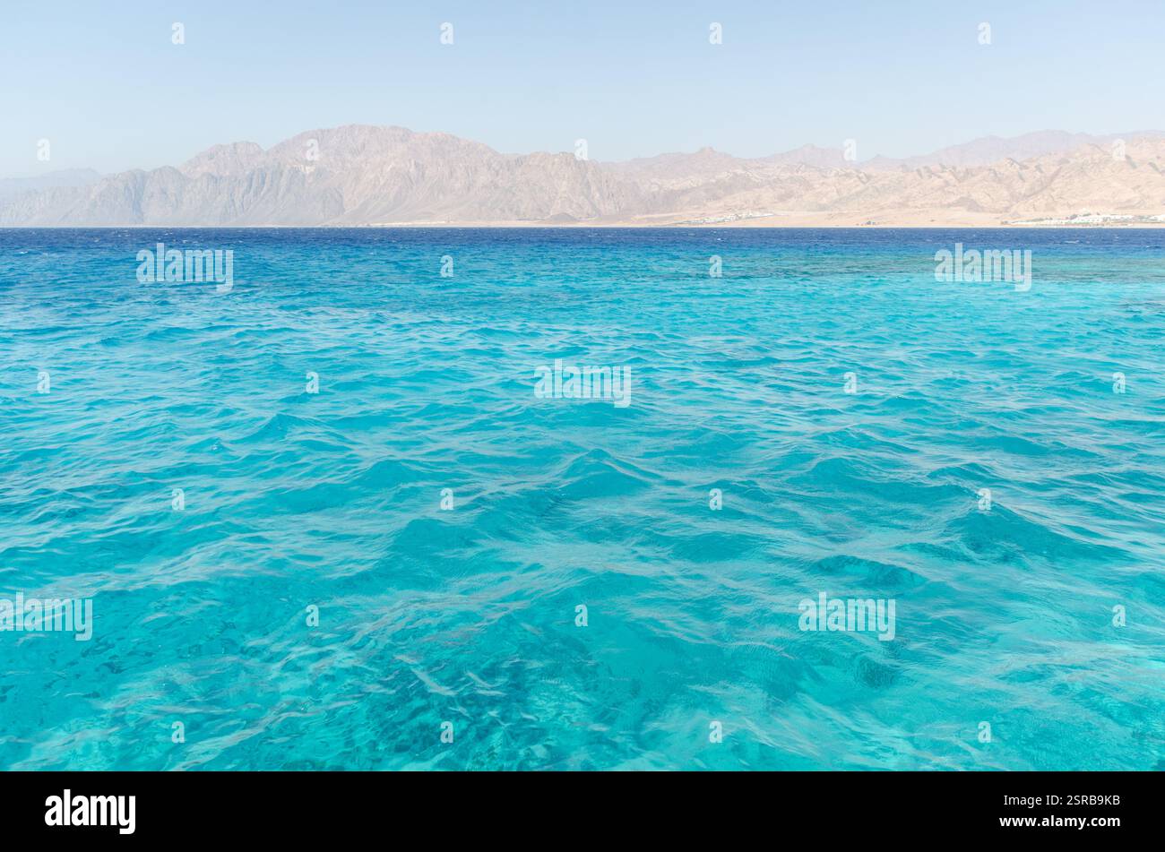 Turquoise waves of Red Sea shimmer under clear daylight, meeting arid ...