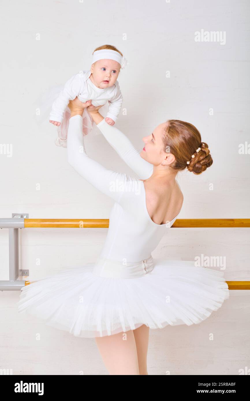 Young adult female ballerina with blonde hair playfully lifts little ...