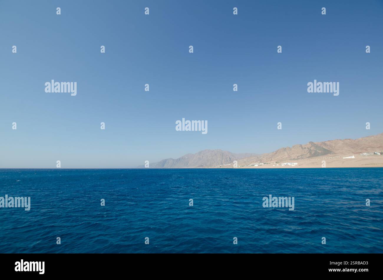 Calm Red Sea under clear sky, with distant mountain range along horizon ...