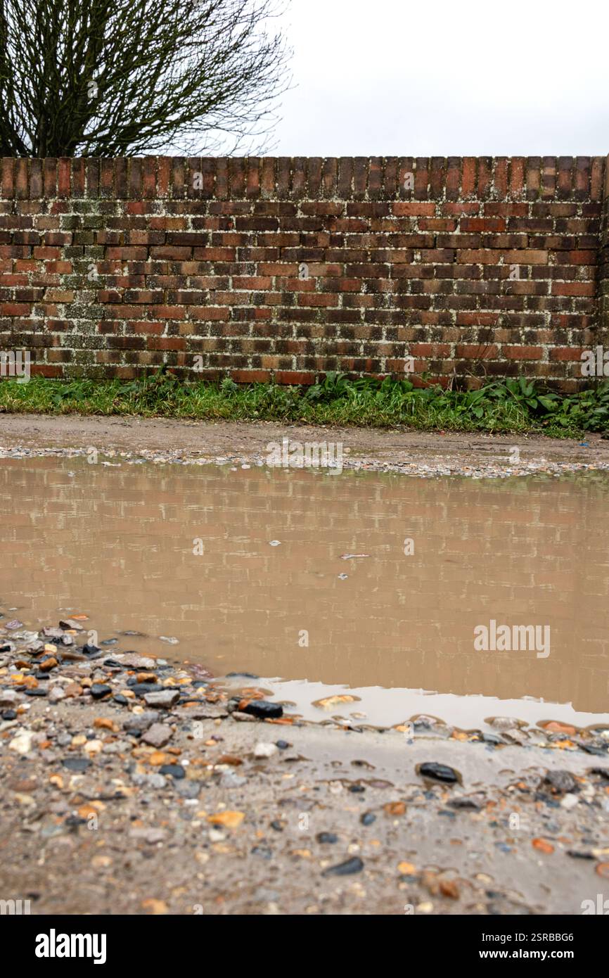 A muddy puddle on a driveway in the winter in the UK Stock Photo - Alamy