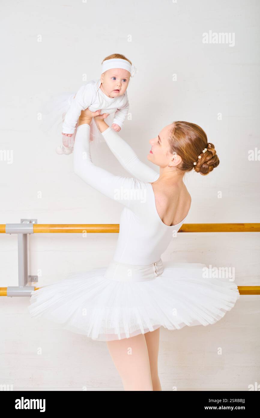 Young adult female ballerina with blonde hair playfully lifts little ...