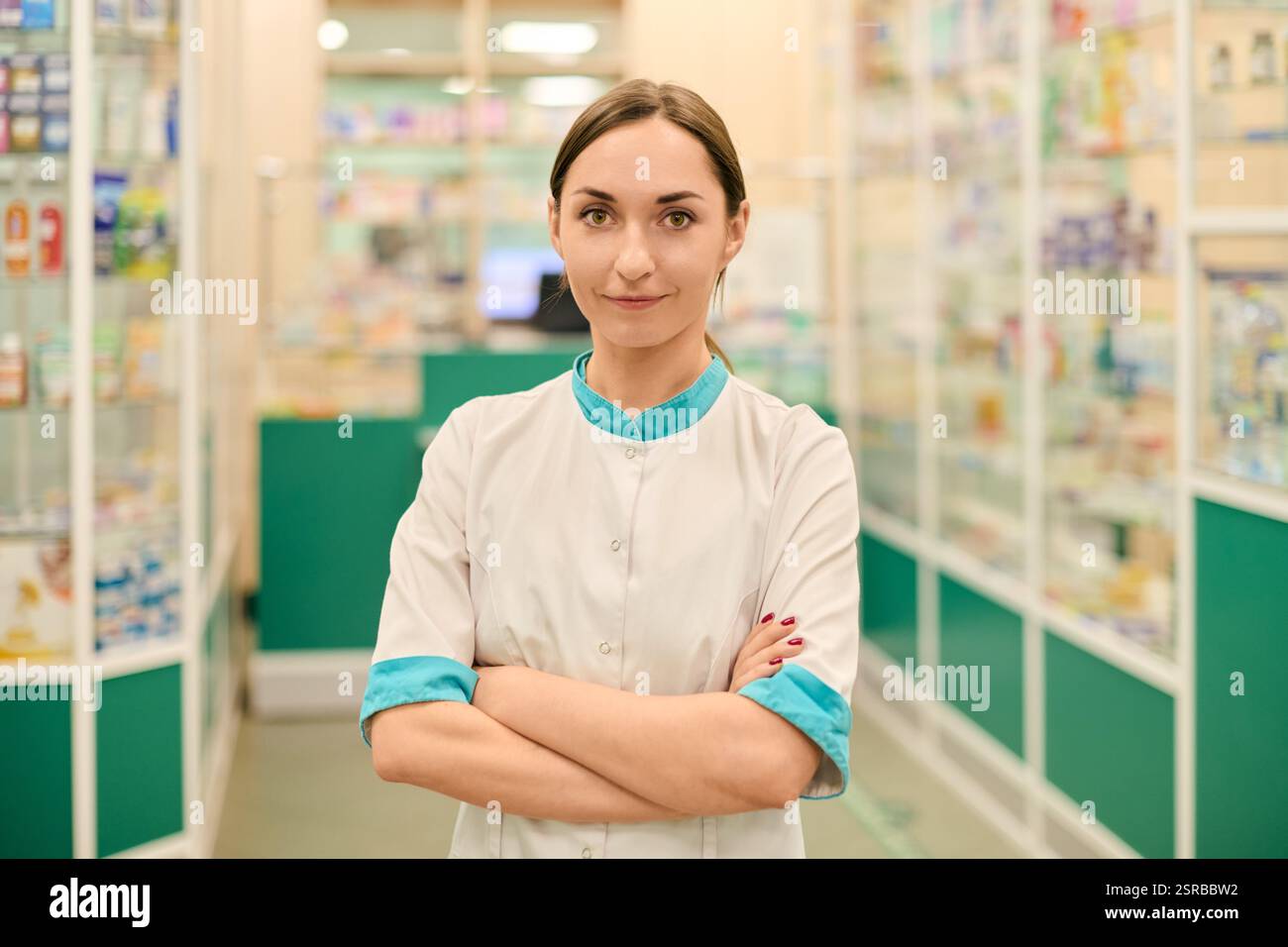 Young caucasian female pharmacist with brown hair stands confidently in ...