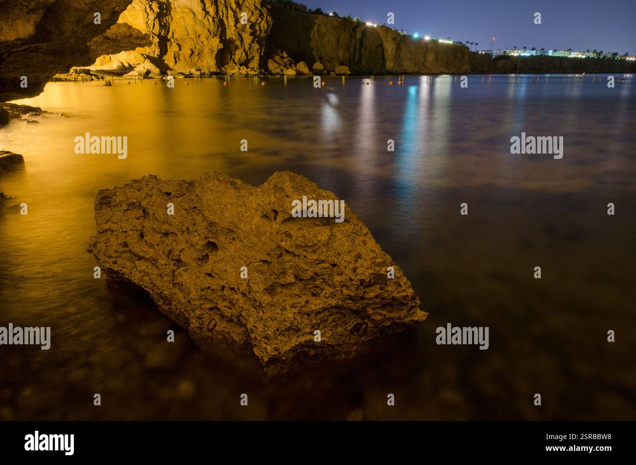 Night view of coastal resort features illuminated rocky shore and ...