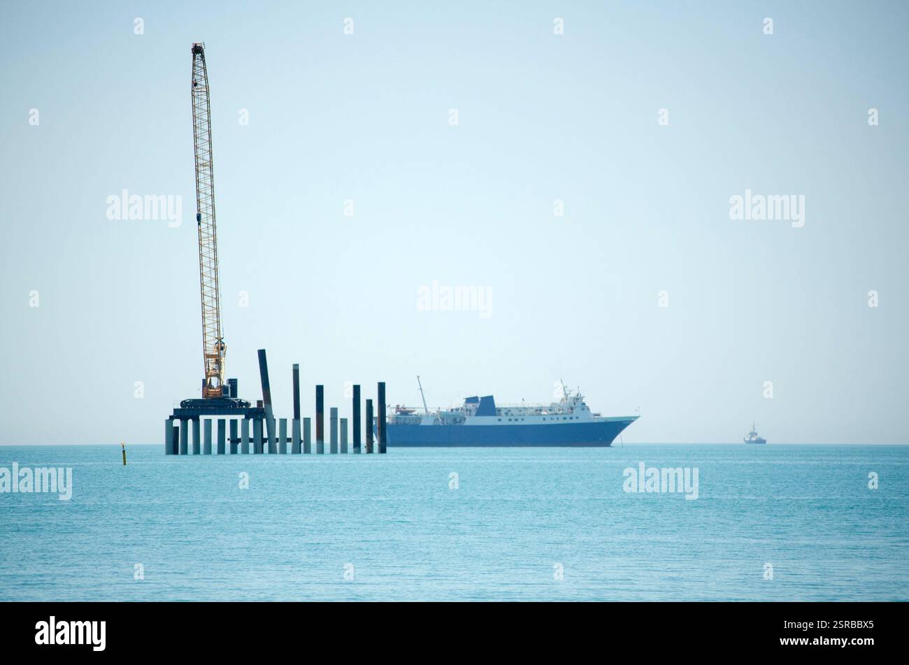 Large ship navigates calm blue sea beside offshore construction. Tall ...