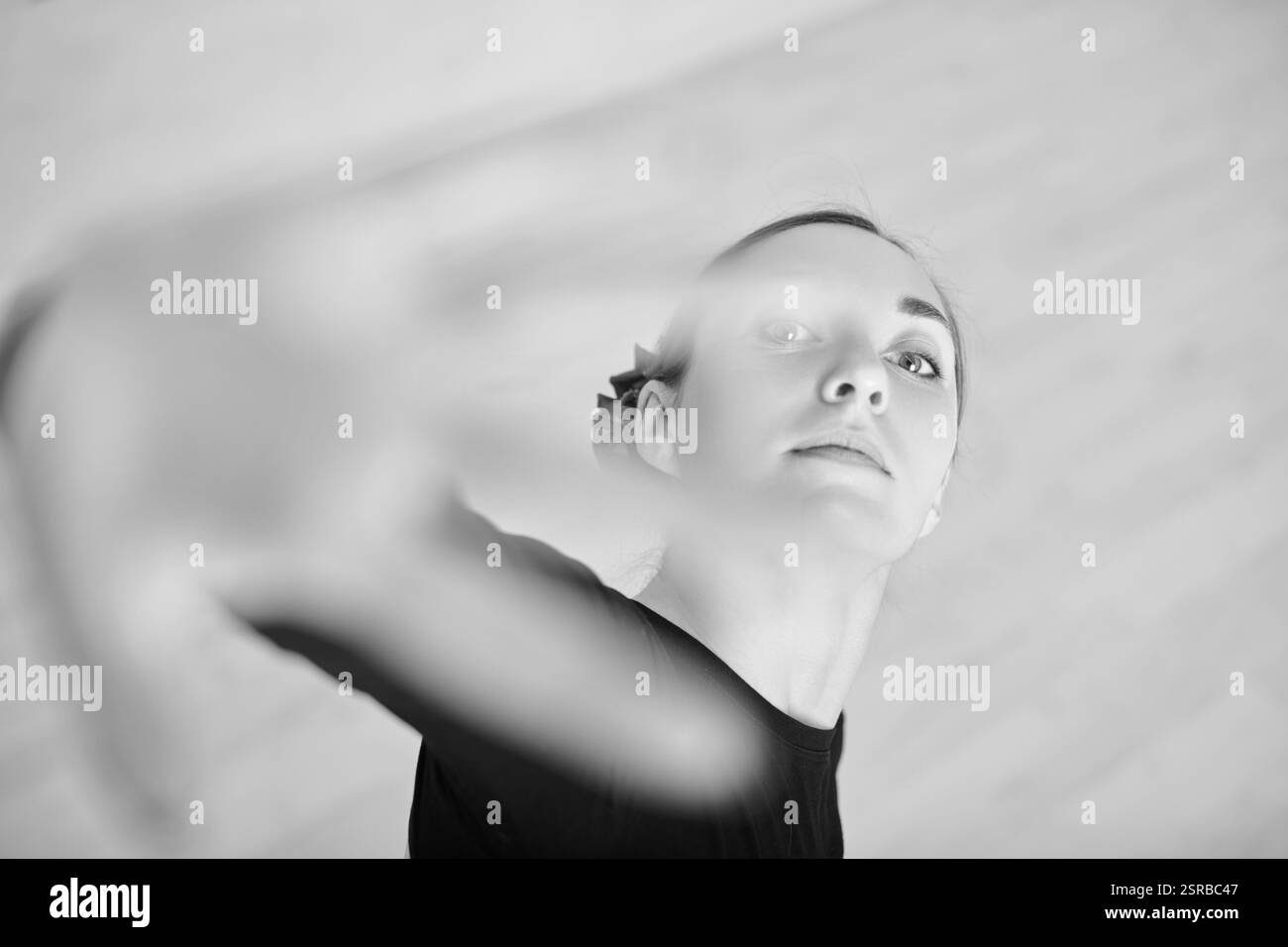 Young adult female ballerina with light hair captured reaching forward ...