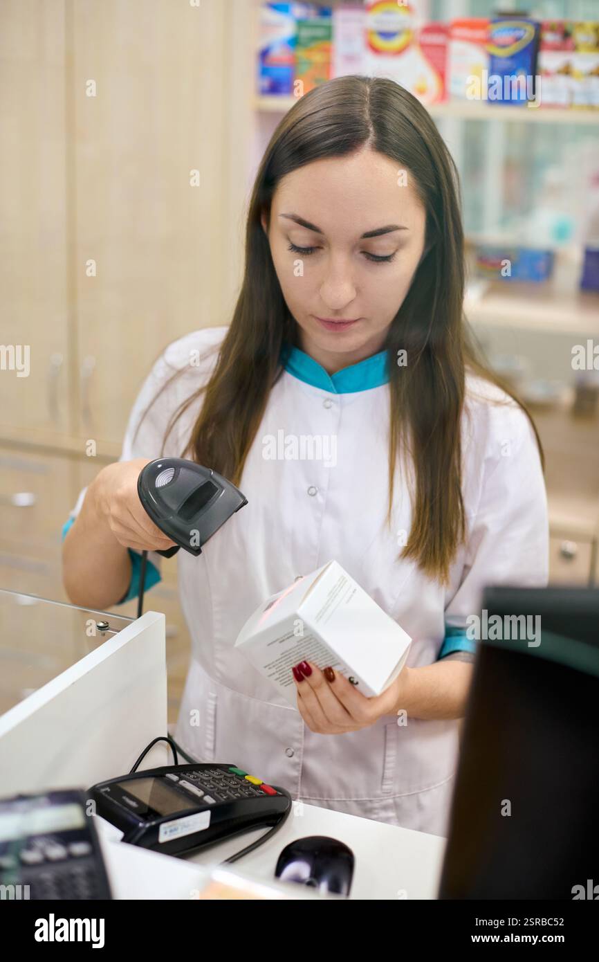 Young female pharmacist with brown hair scans medication package at ...