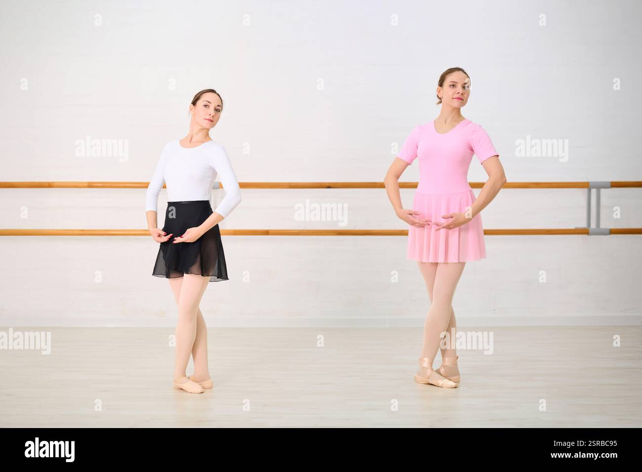Young adult female ballerinas with light hair at ballet barre in dance ...