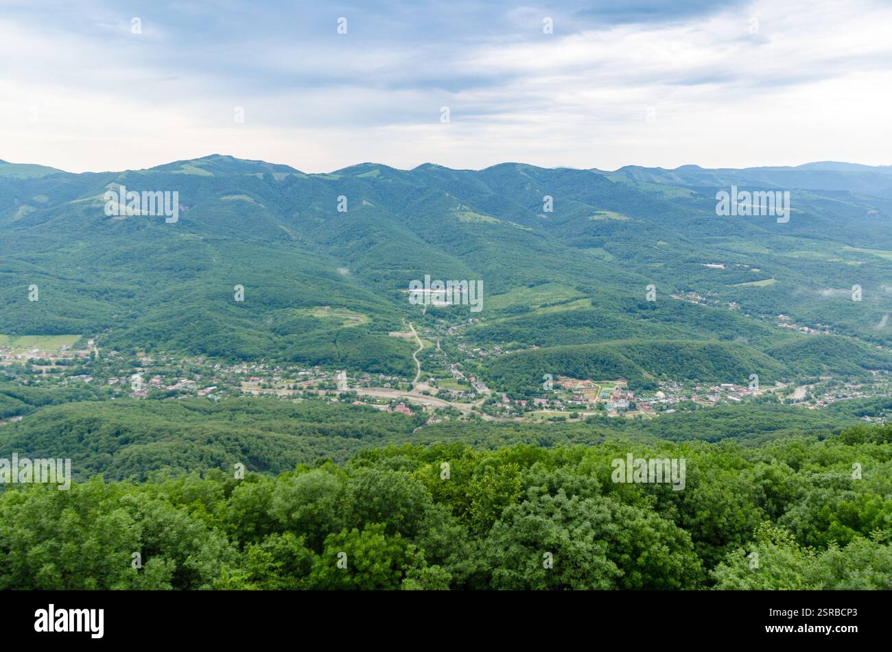 Lush green hills stretch beneath cloudy sky in panoramic view ...