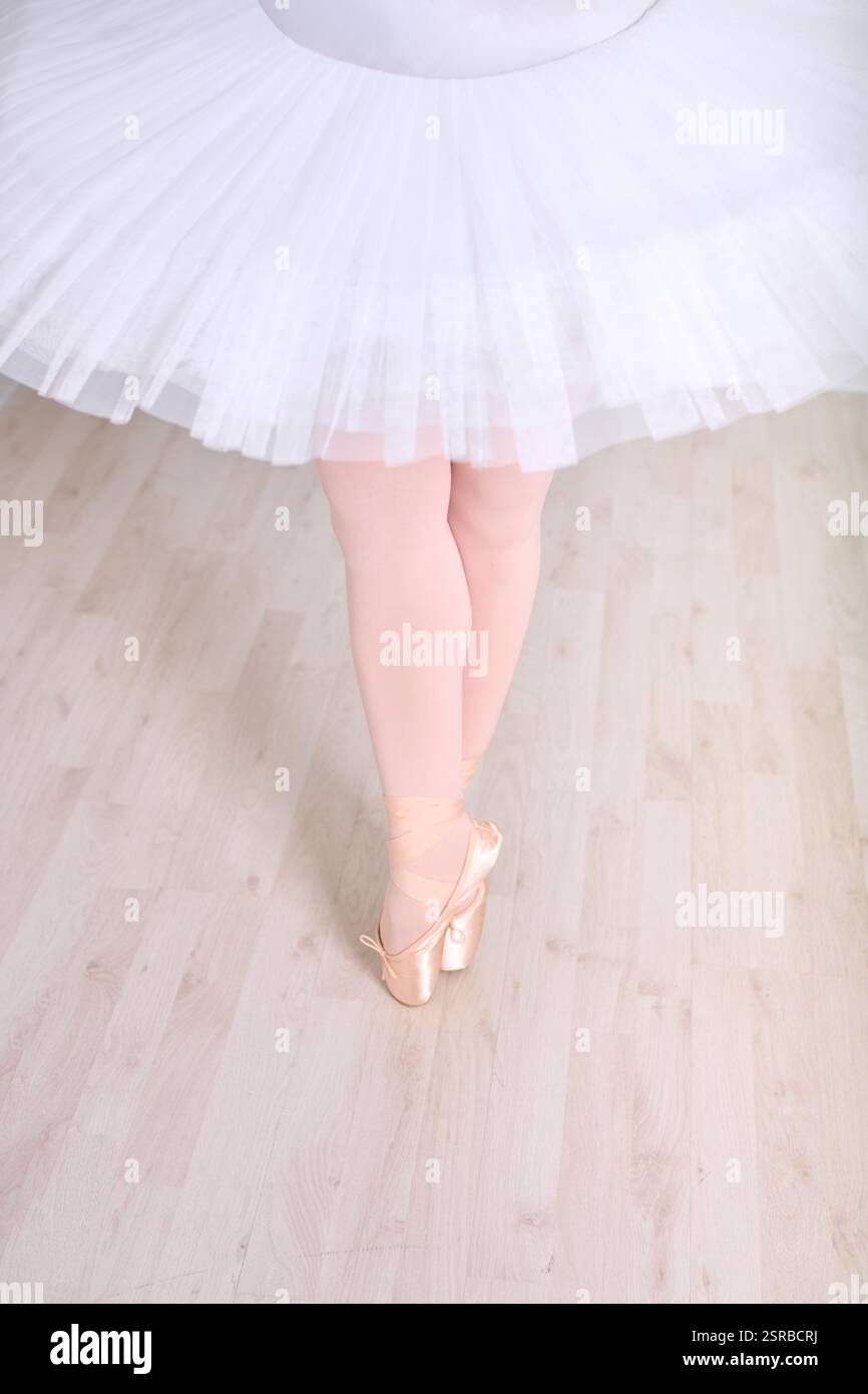 Young female ballerina legs in white tutu holds perfect ballet pose on ...