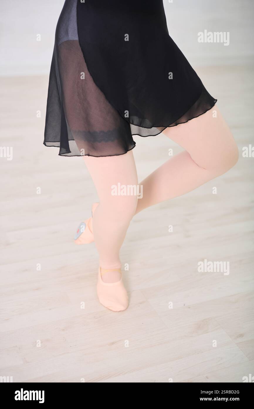 Young female ballerina with white skin, wearing black skirt, practices ...