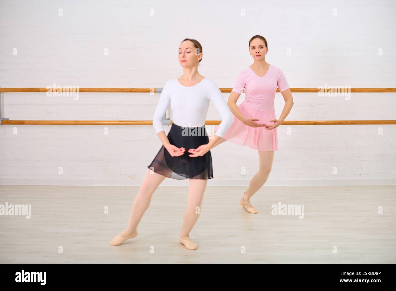 Two young female ballerinas with light hair, in graceful poses at ...