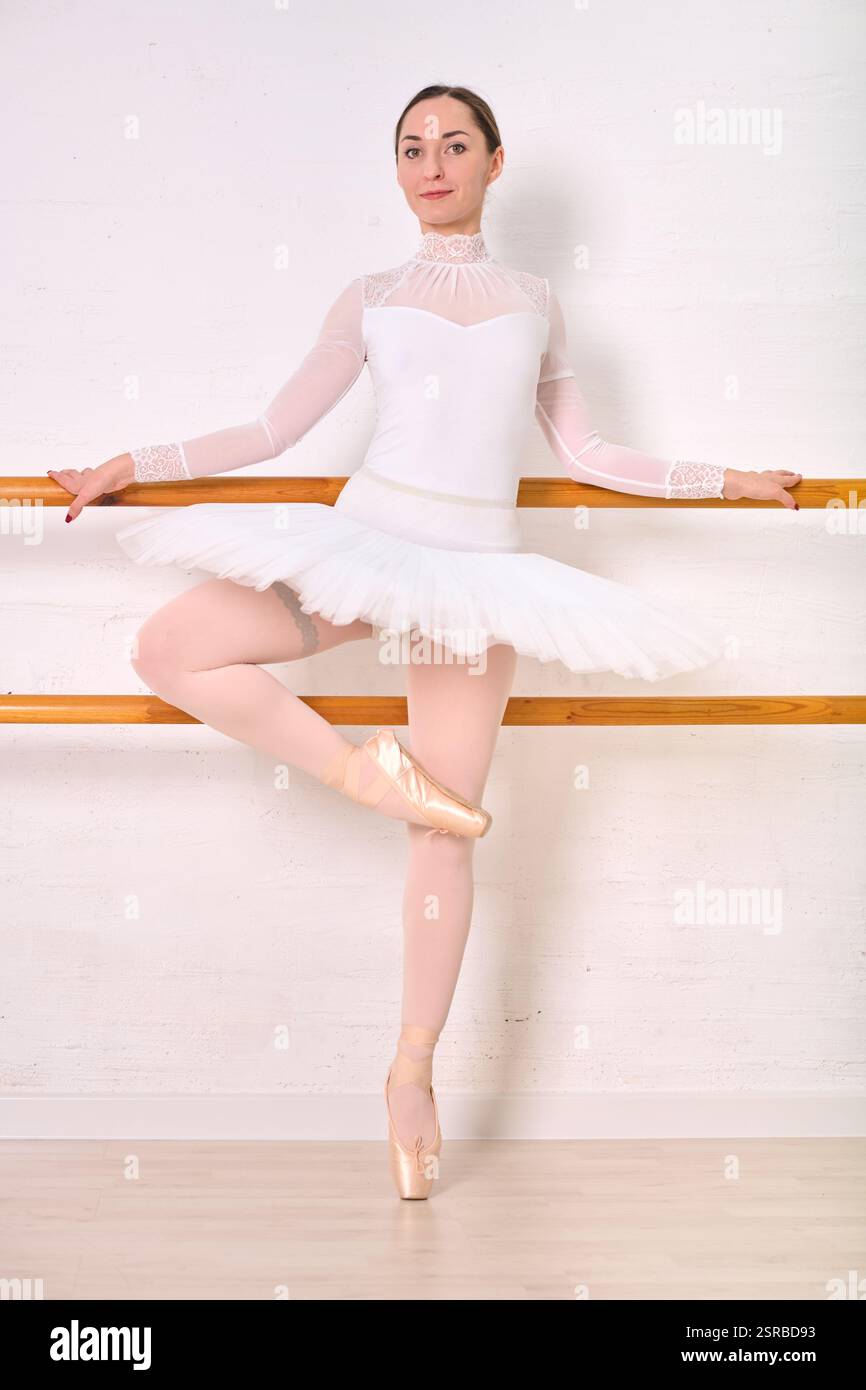 Young adult female ballerina with brown hair stands en pointe at ballet ...