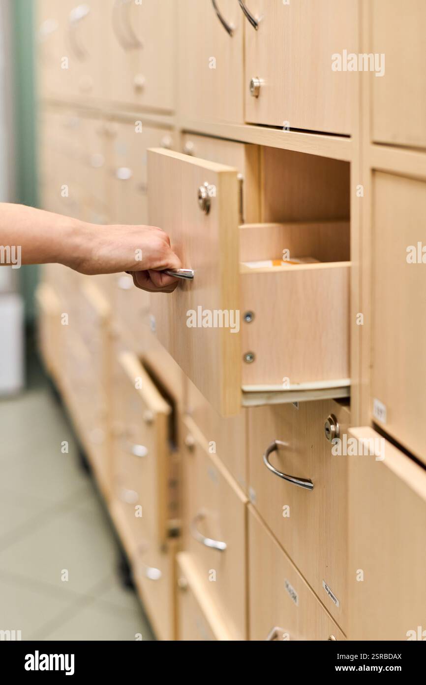 Adult hand with neutral skin tone opening wooden pharmacy drawer ...