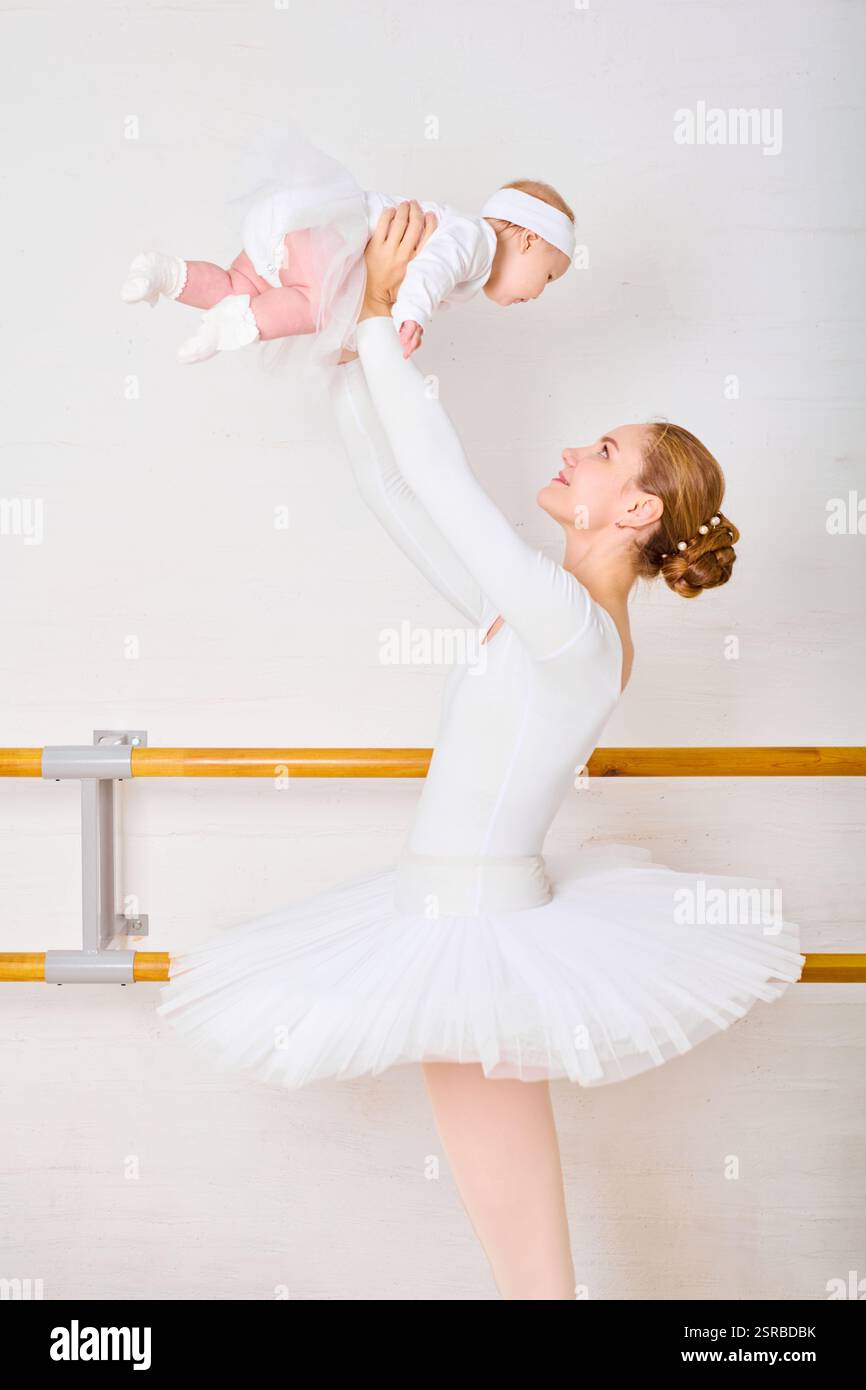 Young adult female ballerina with blonde hair playfully lifts little ...