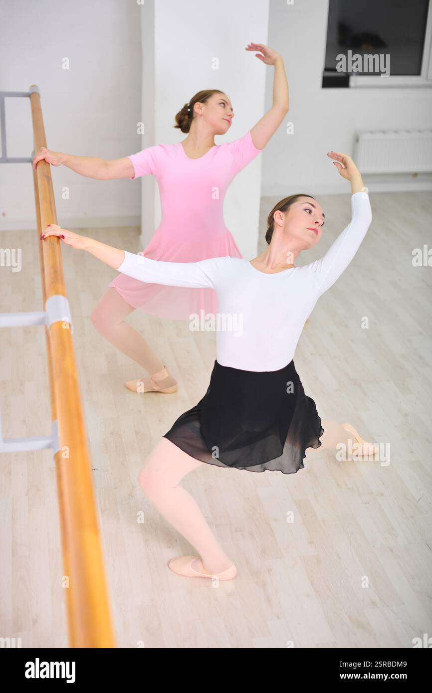 Two young female ballerinas in pink and white dance outfits practice at ...