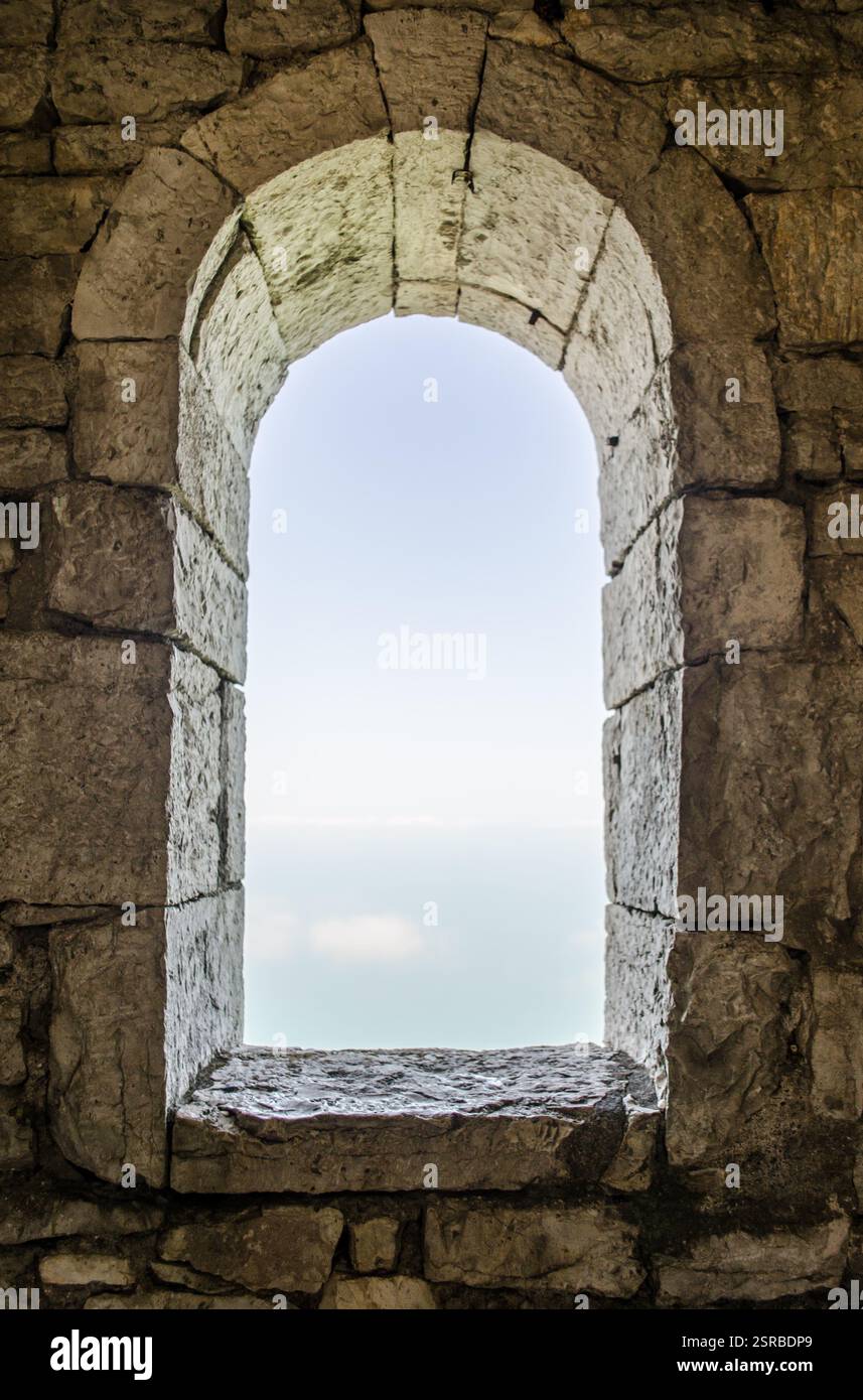 Ancient stone arch window frames clear sky view. Rough wall texture ...