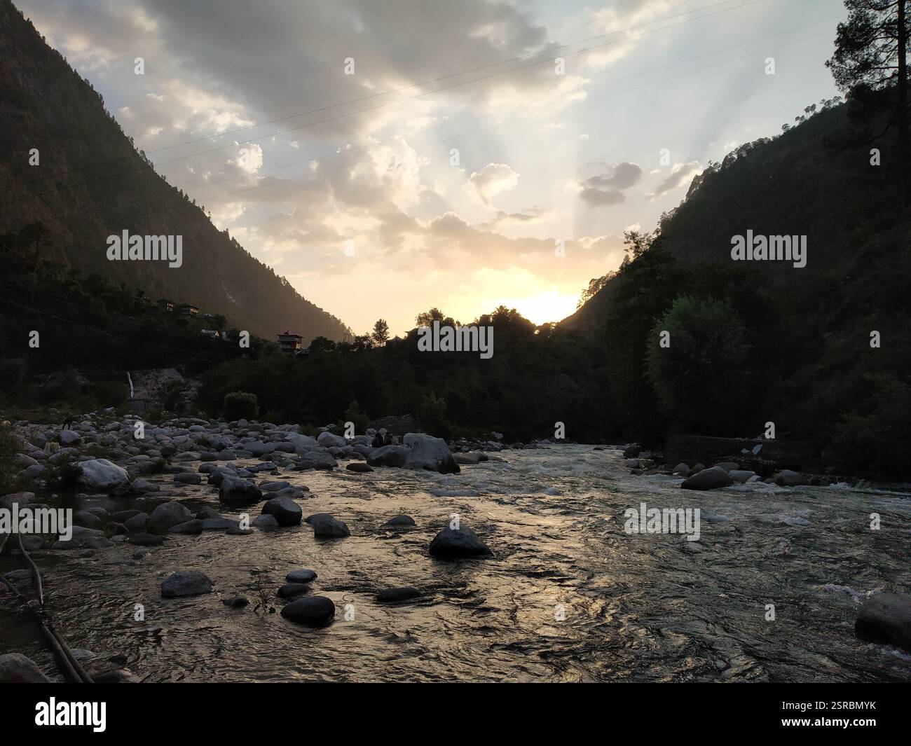 Sunset behind mountains and water running down the stream Stock Photo ...