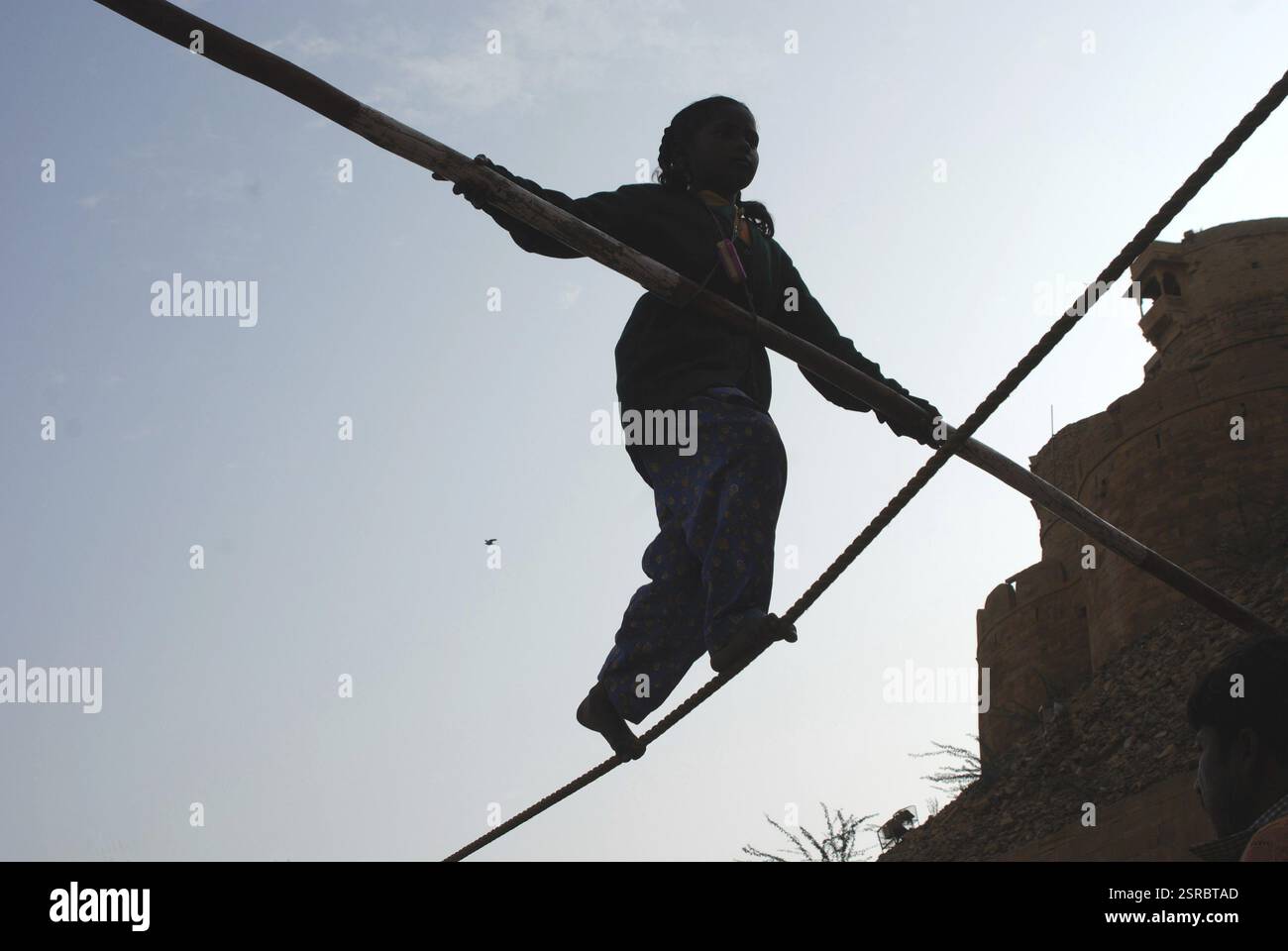 Girl balancing with bamboo in hand on rope, Jaisalmer, Rajasthan, India ...