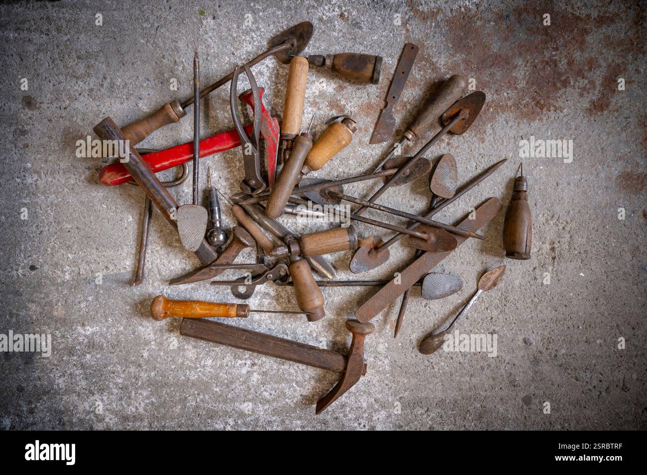 Old shoemaker tools in a pile on the concrete floor Stock Photo - Alamy