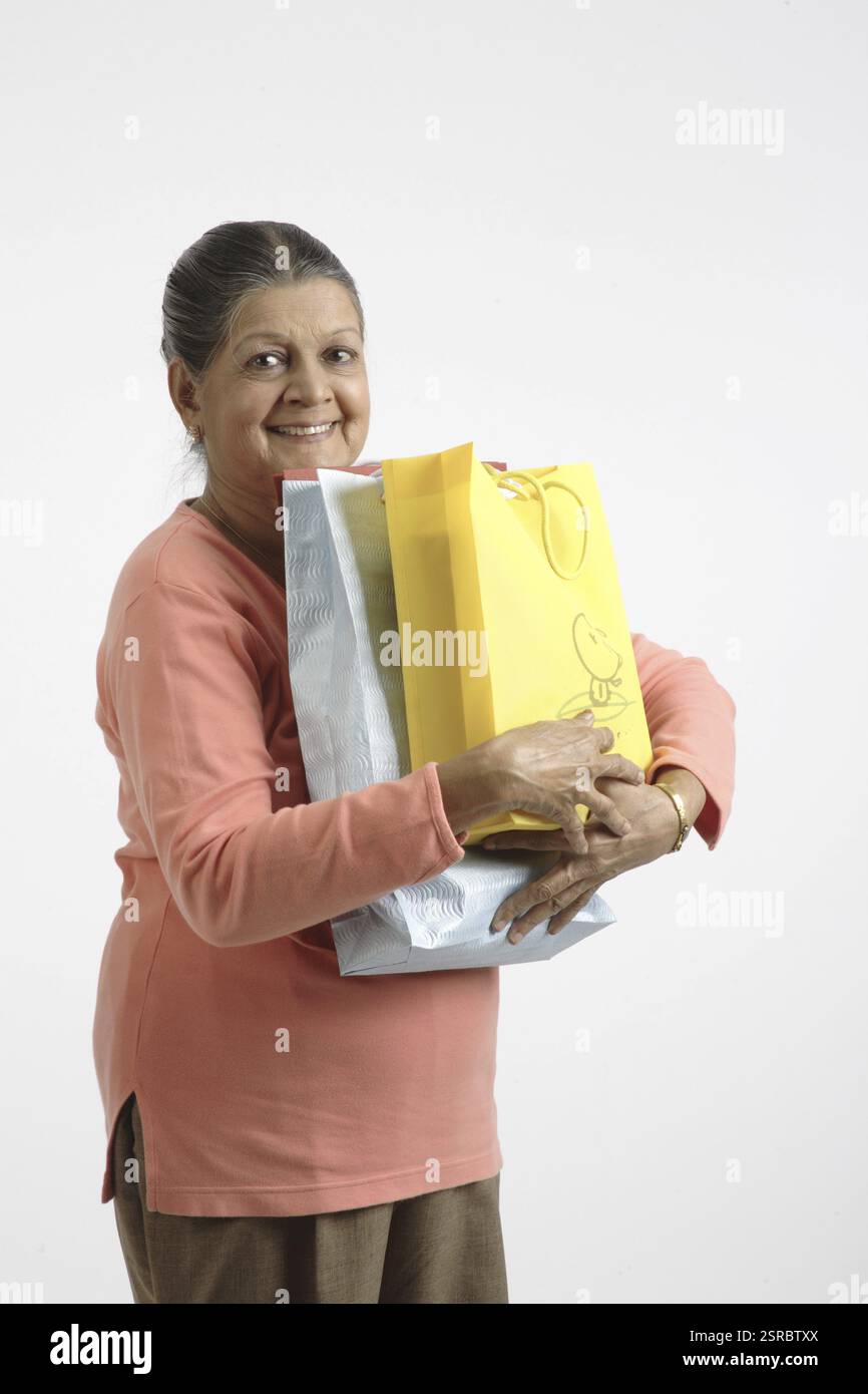 Old lady holding colourful shopping bags near her chest and smiling MR ...