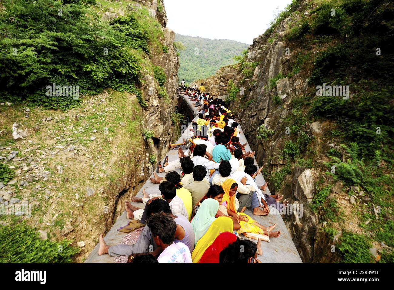 Commuters sitting on roof of train going through cliff, Kamali Ghat ...