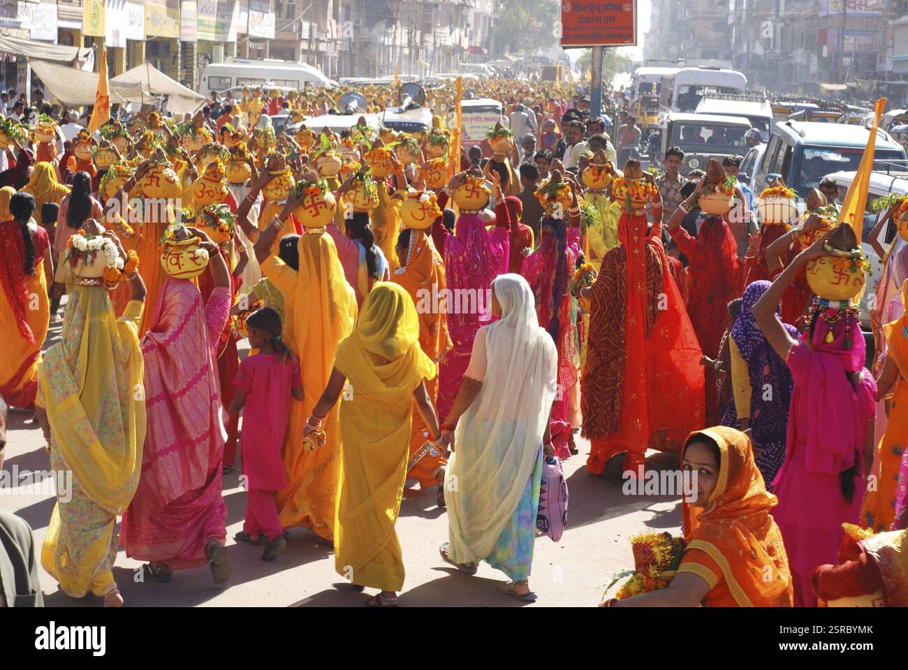 Ladies in colourful sari carrying yellow pitcher on head, Rajasthan ...
