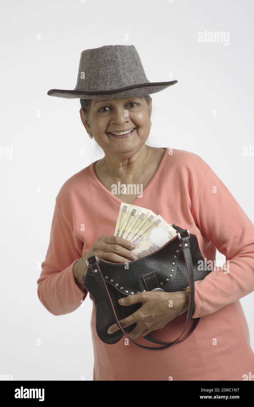 Old lady holding in one hand five notes of Rs.500 each and other hand ...