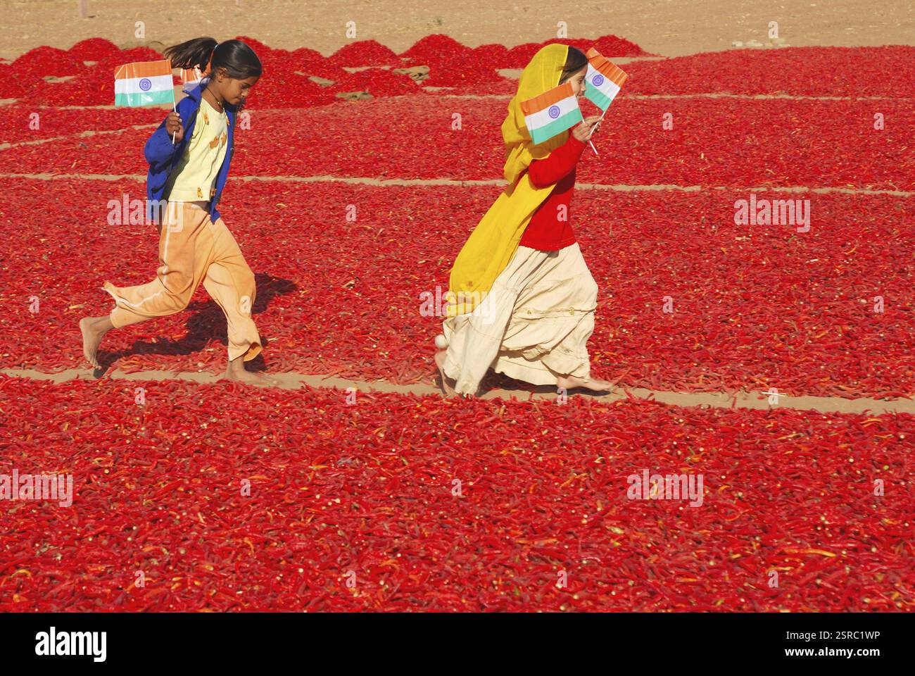 Girls running across red chilli pepper with national flags in hands ...