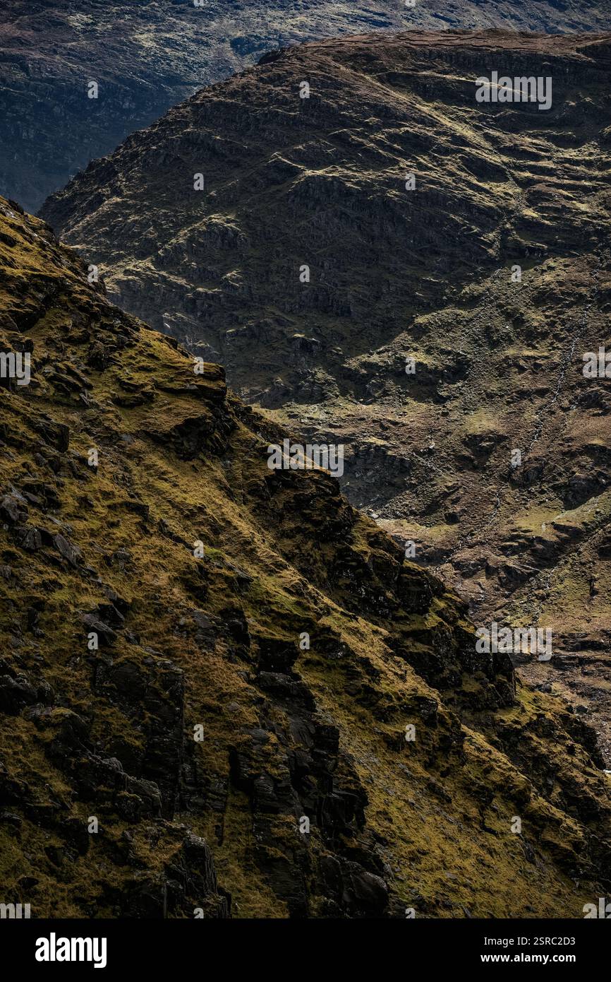 Textured mountain landscape with rocky slopes and grassy patches in a ...