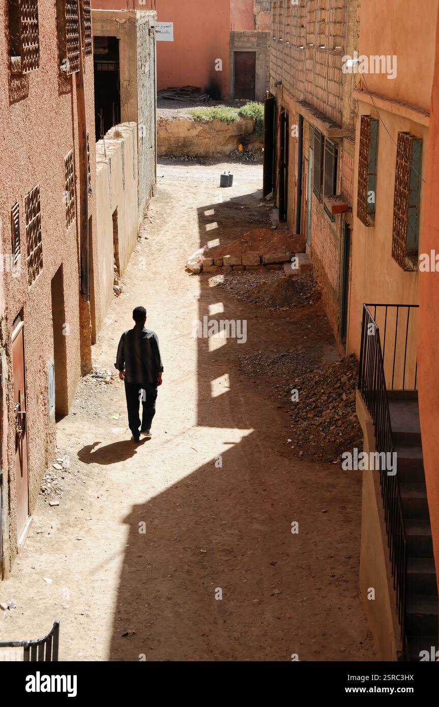 Oasis town in the Todra Gorge, A man walks through a narrow alley lined ...