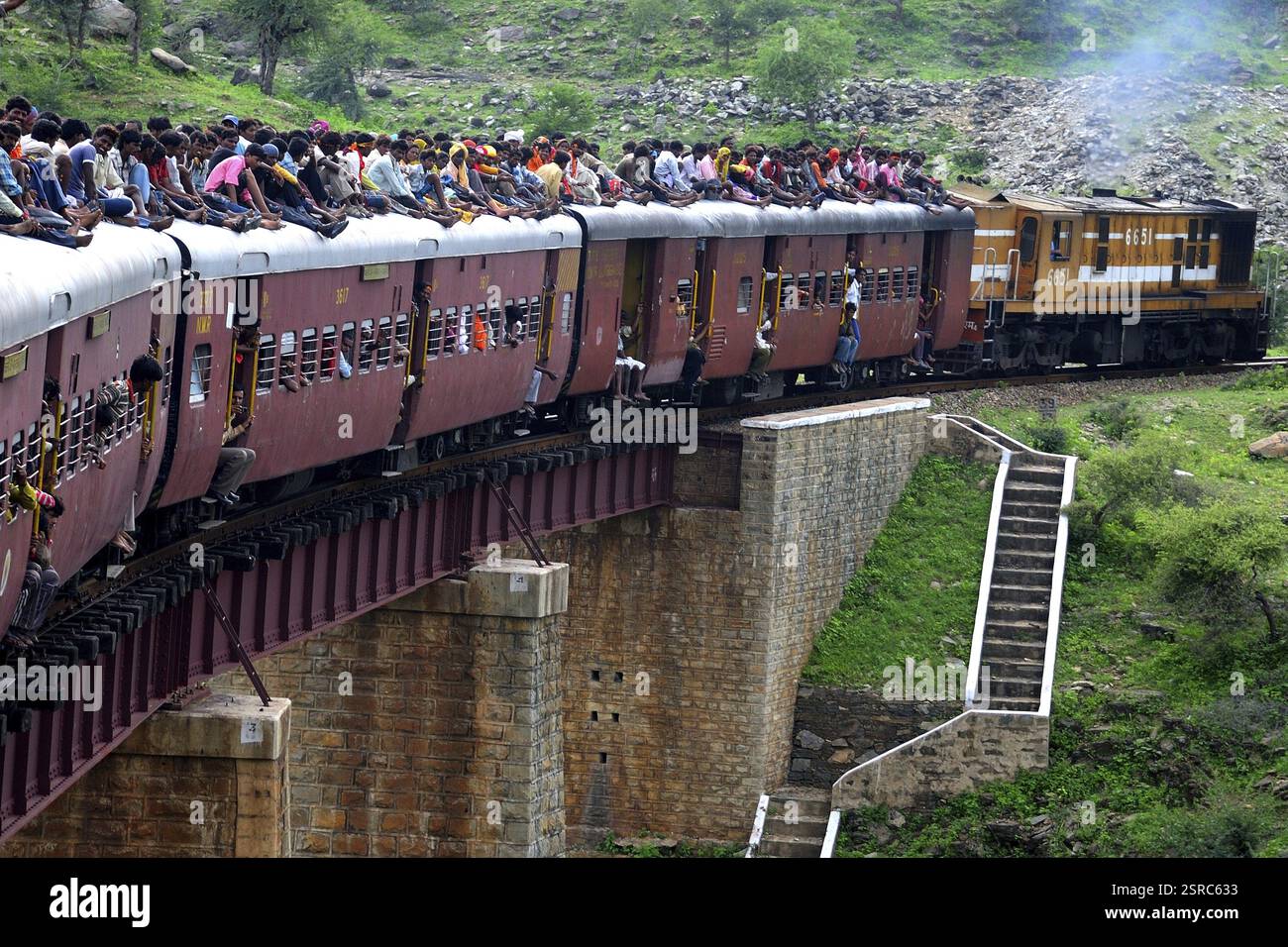Commuters sitting on roof of train on bridge, Kamali Ghat, Rajasthan ...