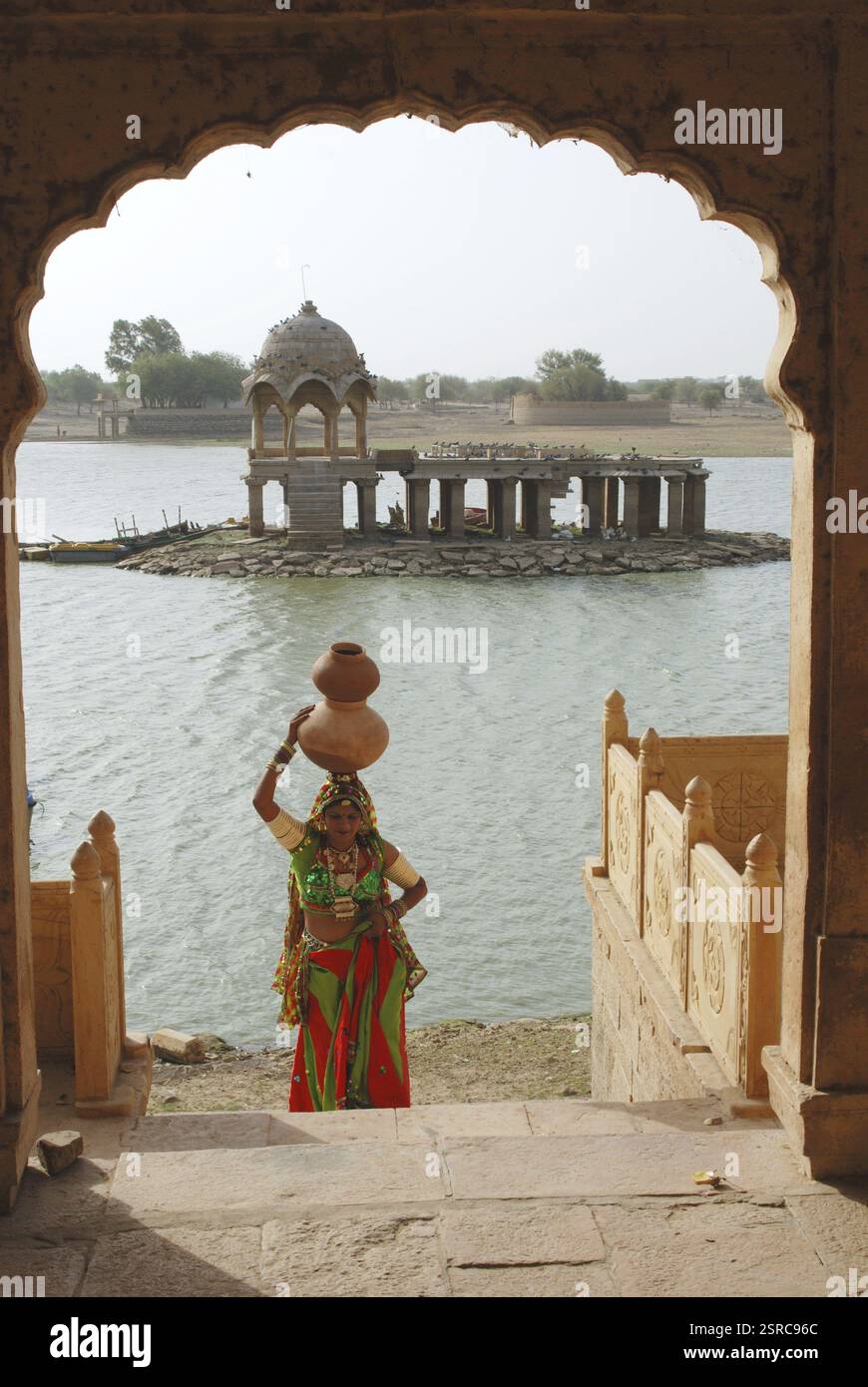 A woman in traditional Rajasthani dress with pitchers on her head ...