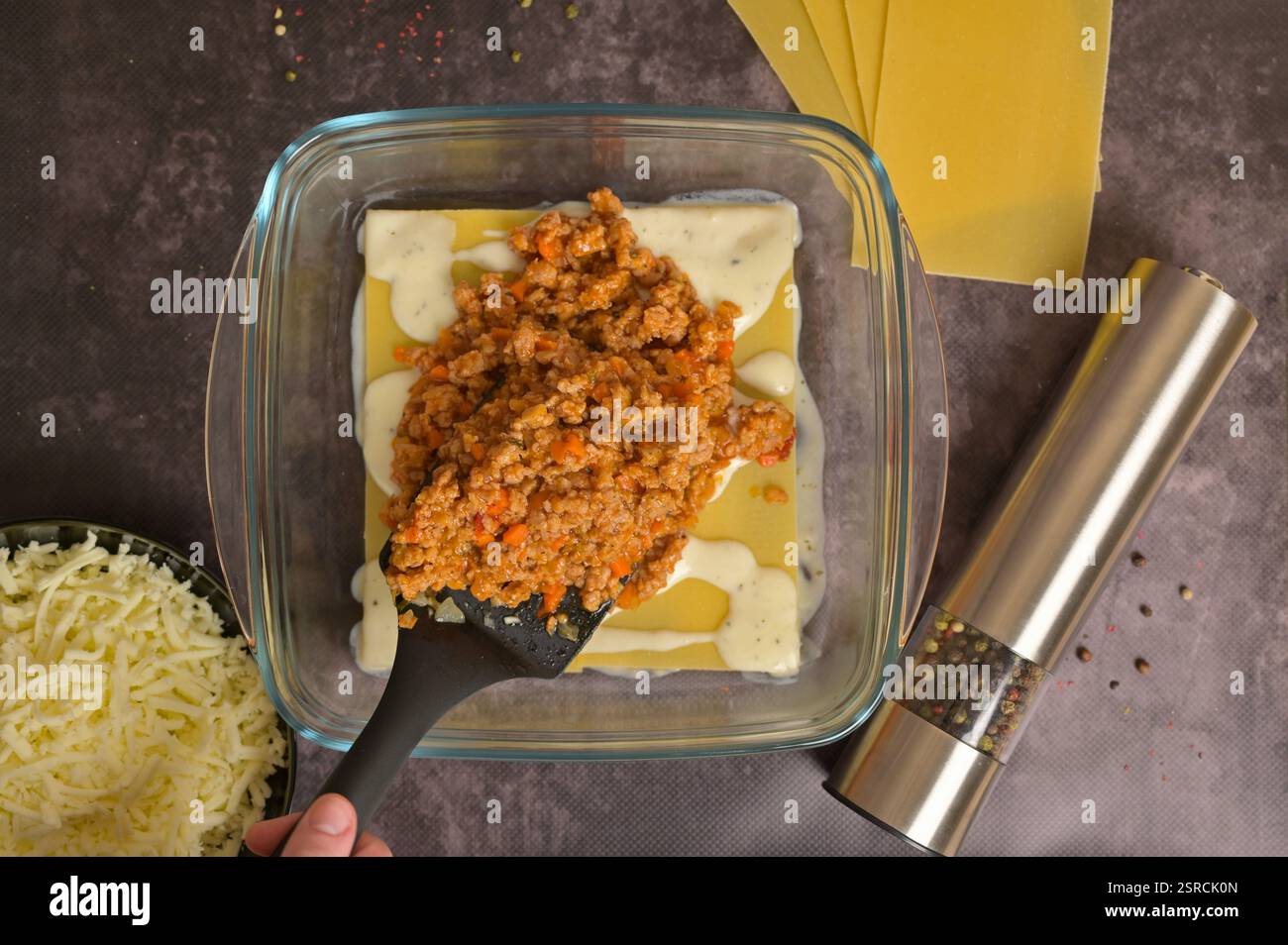 Homemade lasagna cooking preparation. Woman's hand use a spatula to ...