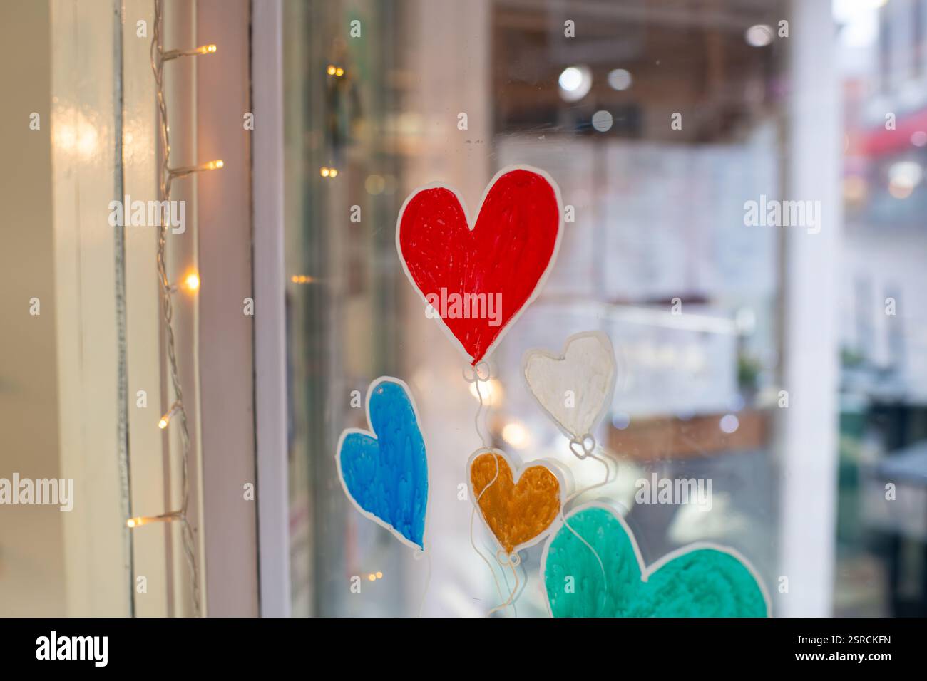 A window with a heart painted on it and a bunch of other hearts. The ...