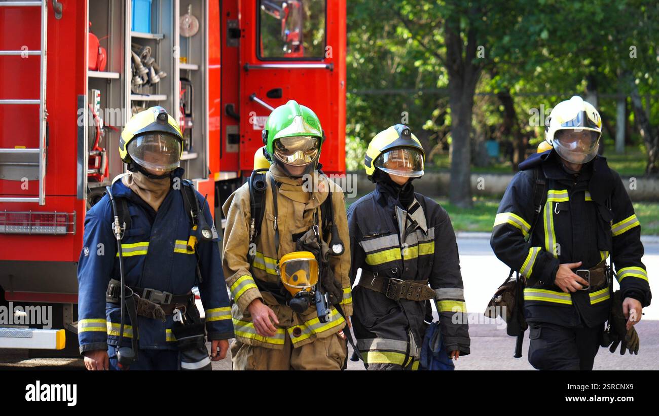 Tired male and female fireguards in full equipment walk after putting ...