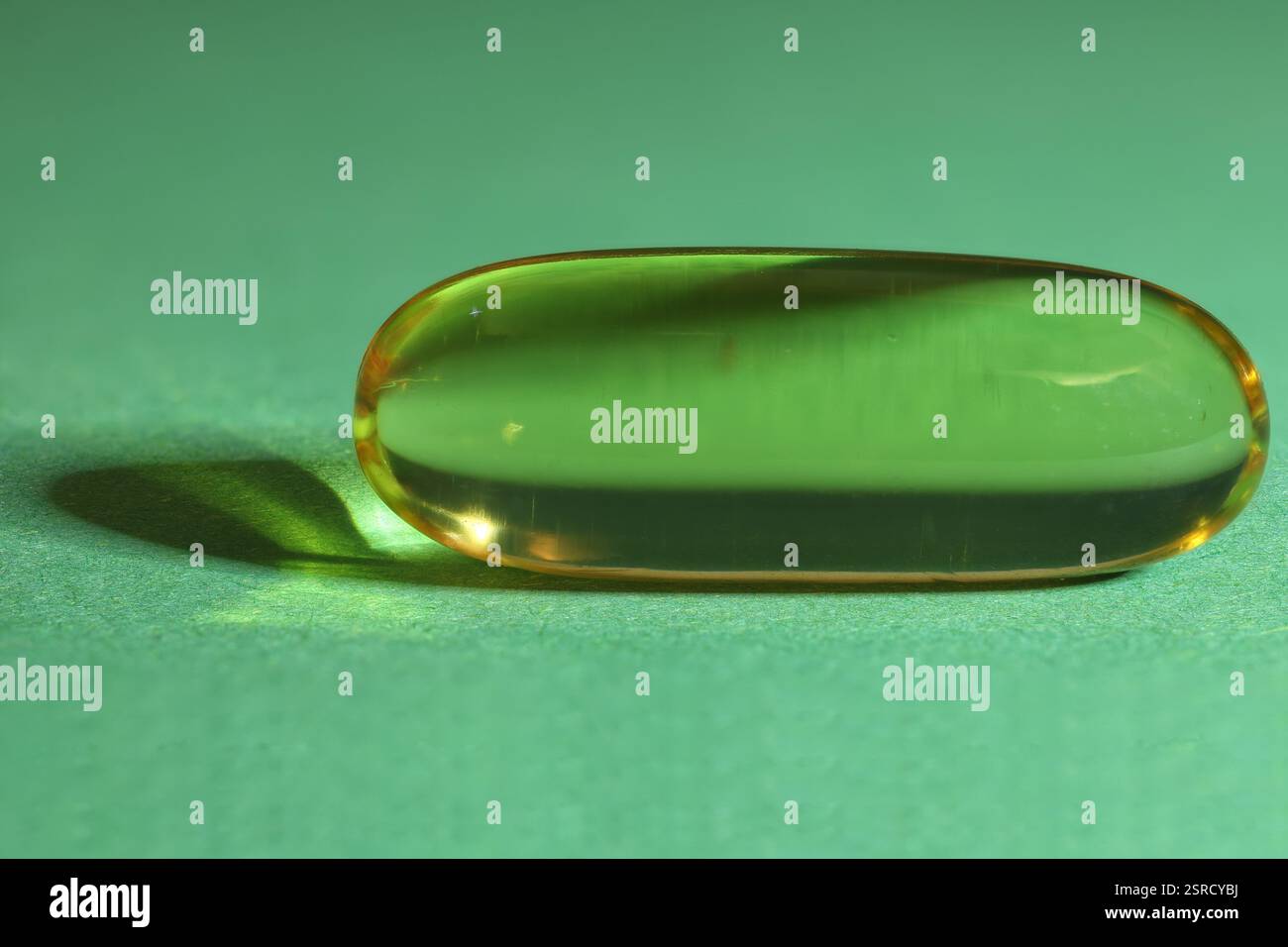 Macro of yellow gel capsule pill on green background, with great depth ...