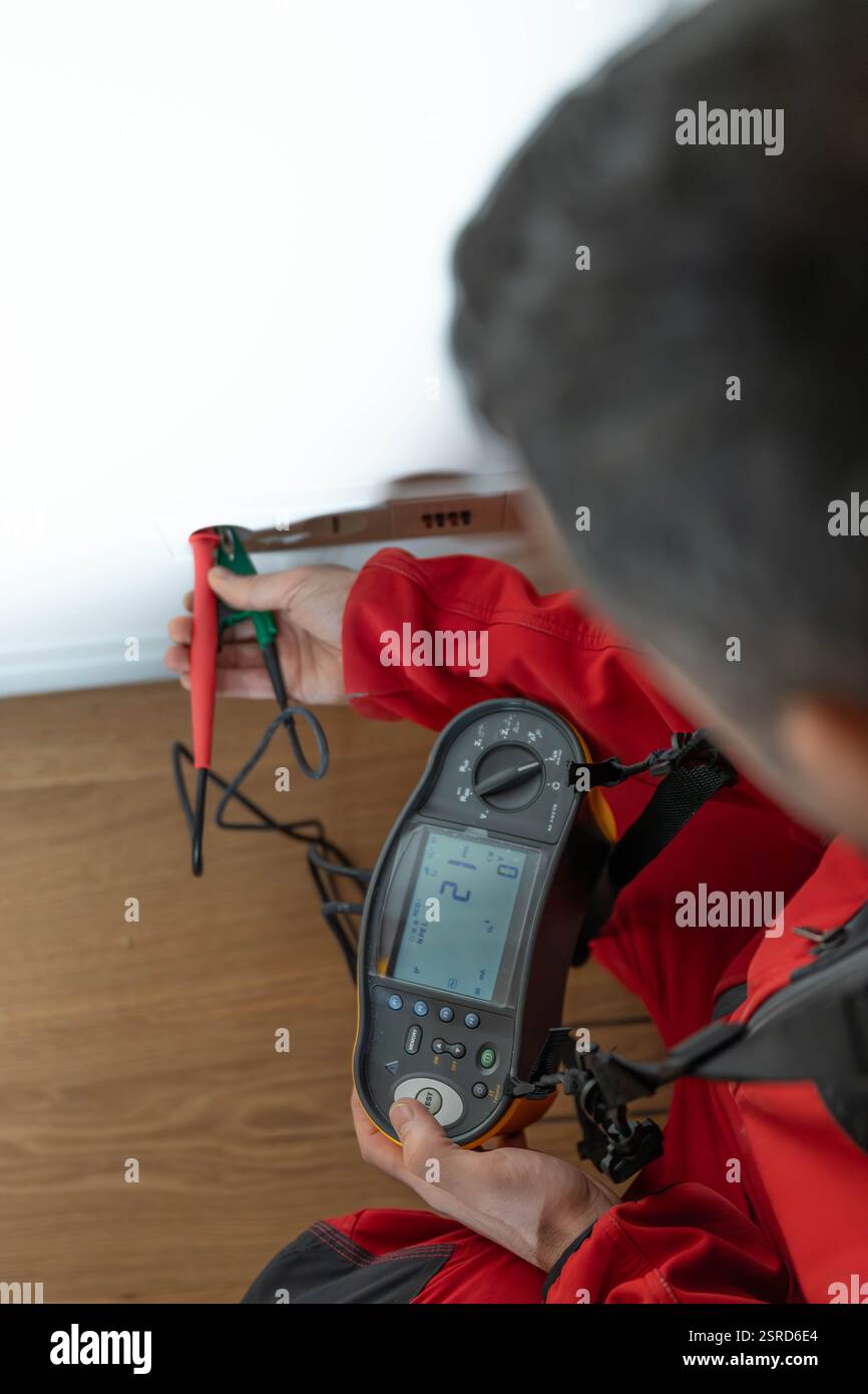 Electrician tests socket voltage with a specialized device, ensuring ...