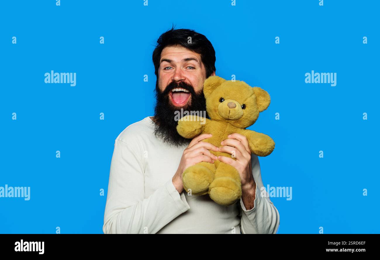 Teddy bear toy. Smiling bearded man in white sweater with plush teddy ...