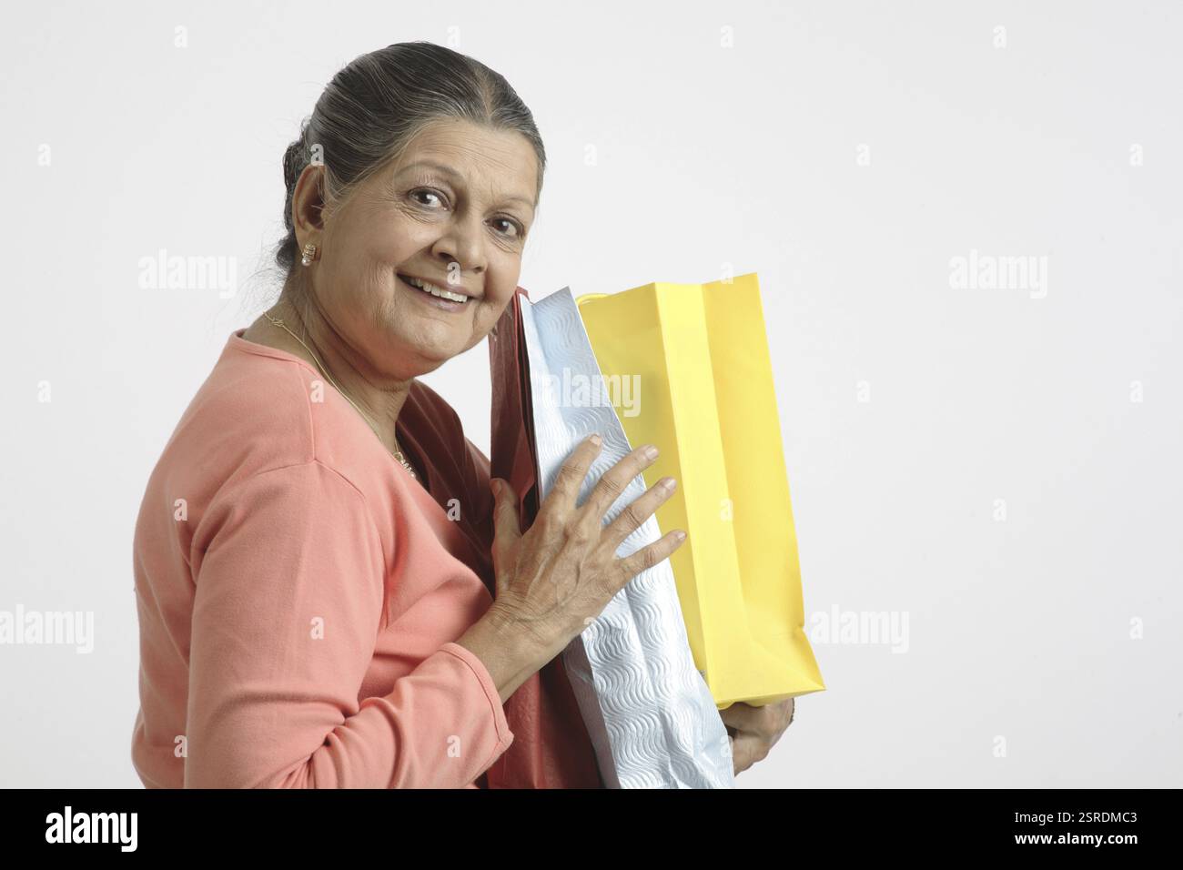 Old lady holding colourful shopping bags near her chest and smiling MR ...