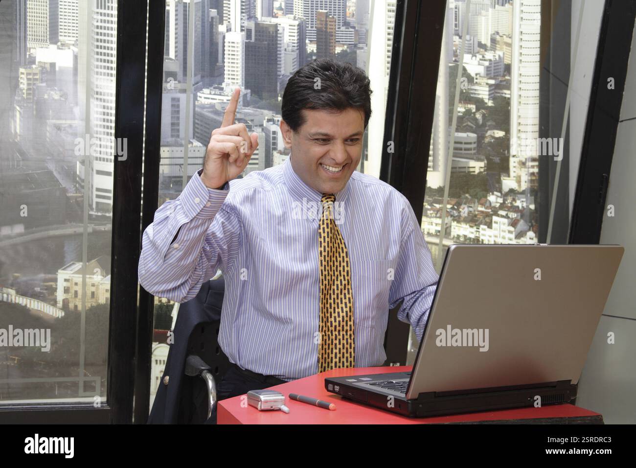 Executive looking at laptop screen pointing index finger at top in ...