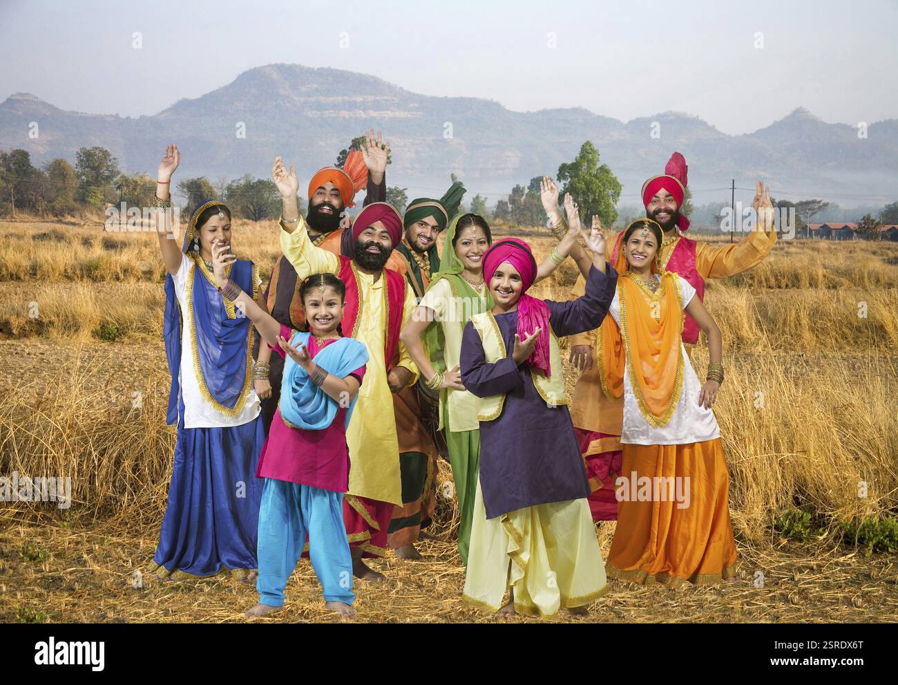 Sikh family with dancers performing folk dance bhangra in dry grass MR ...